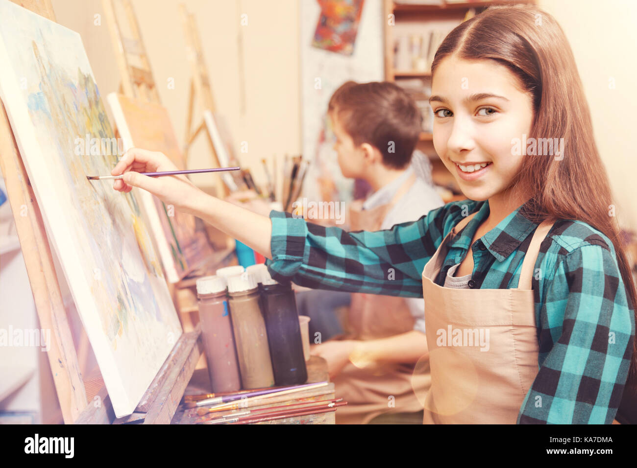 Smiling girl with painting brush looking into camera Stock Photo - Alamy