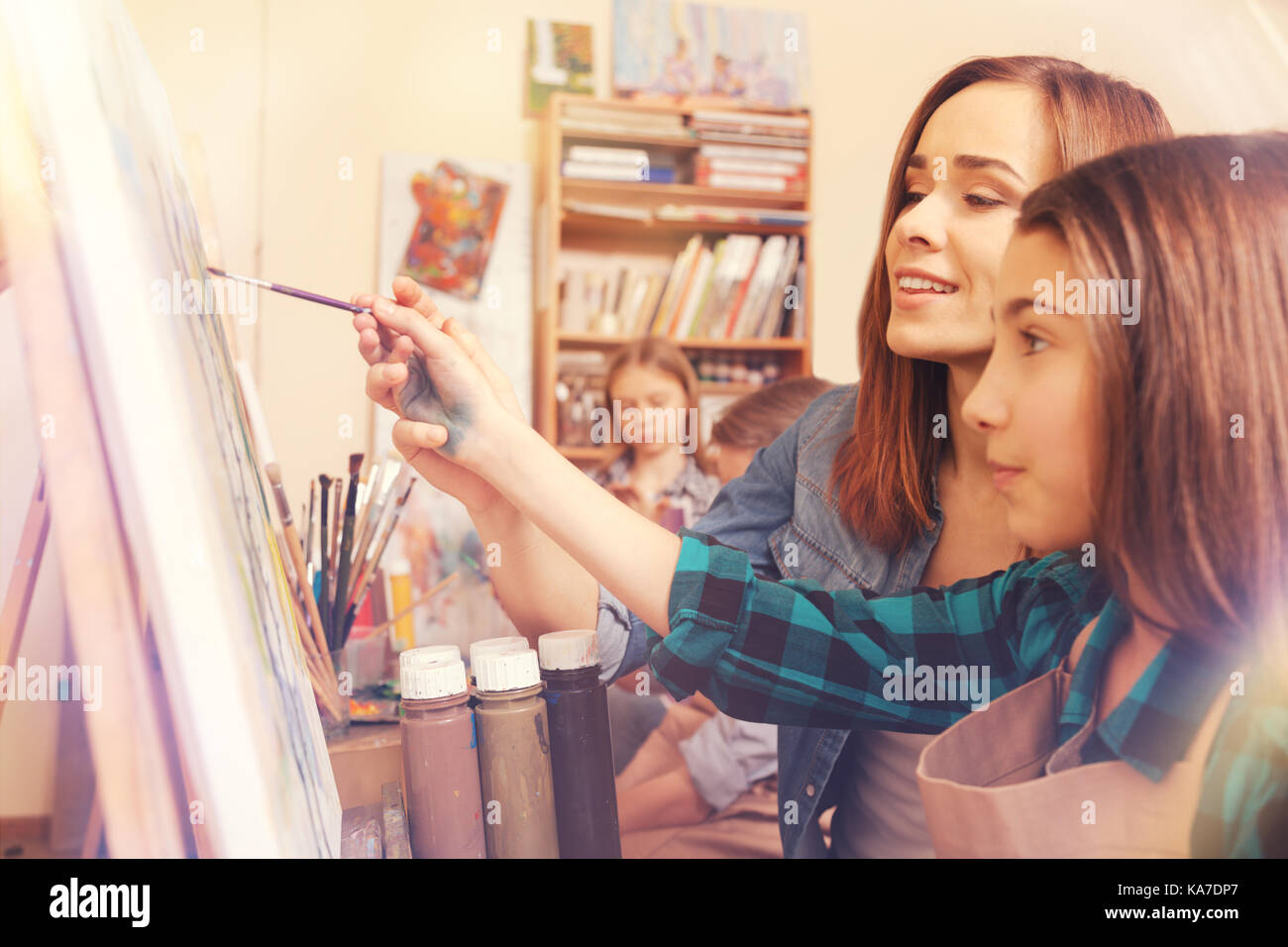 Female artist helping young student with abstract painting Stock Photo ...