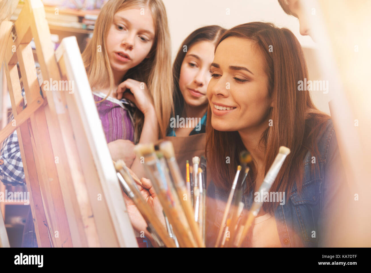 Curious children looking at young female artist painting Stock Photo ...