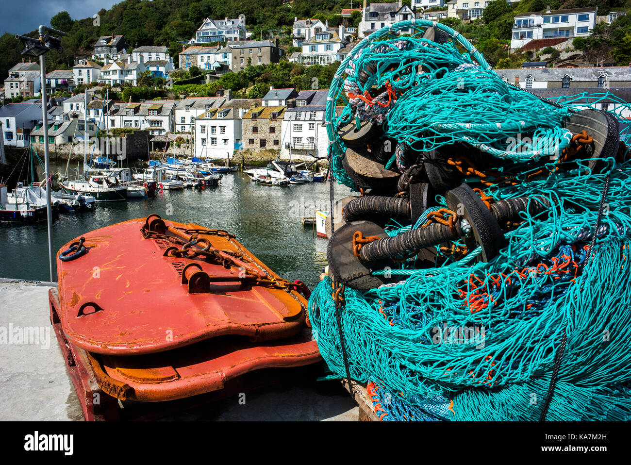 fishing nets in blue plastic boxes on quayside with harbour cottages in ...