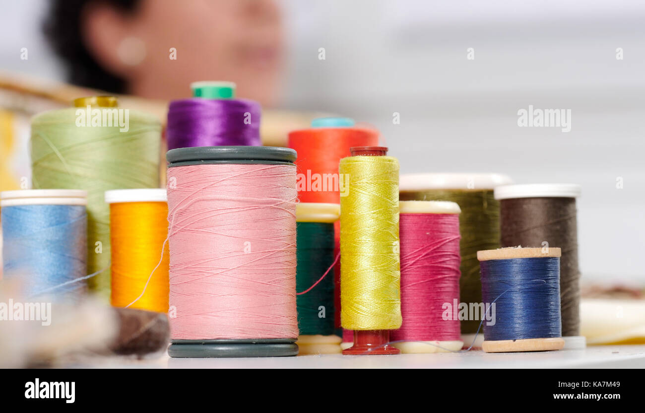 Many reels of colored threads, seamstress at the bottom Stock Photo - Alamy