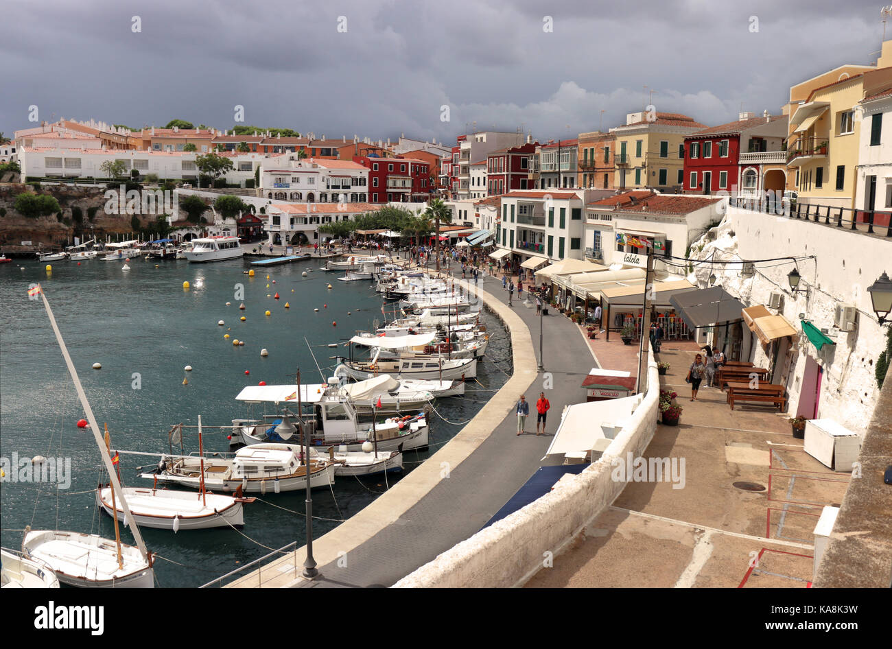 Es Castell in Minorca with fishing boats and yachts moored on the quay ...
