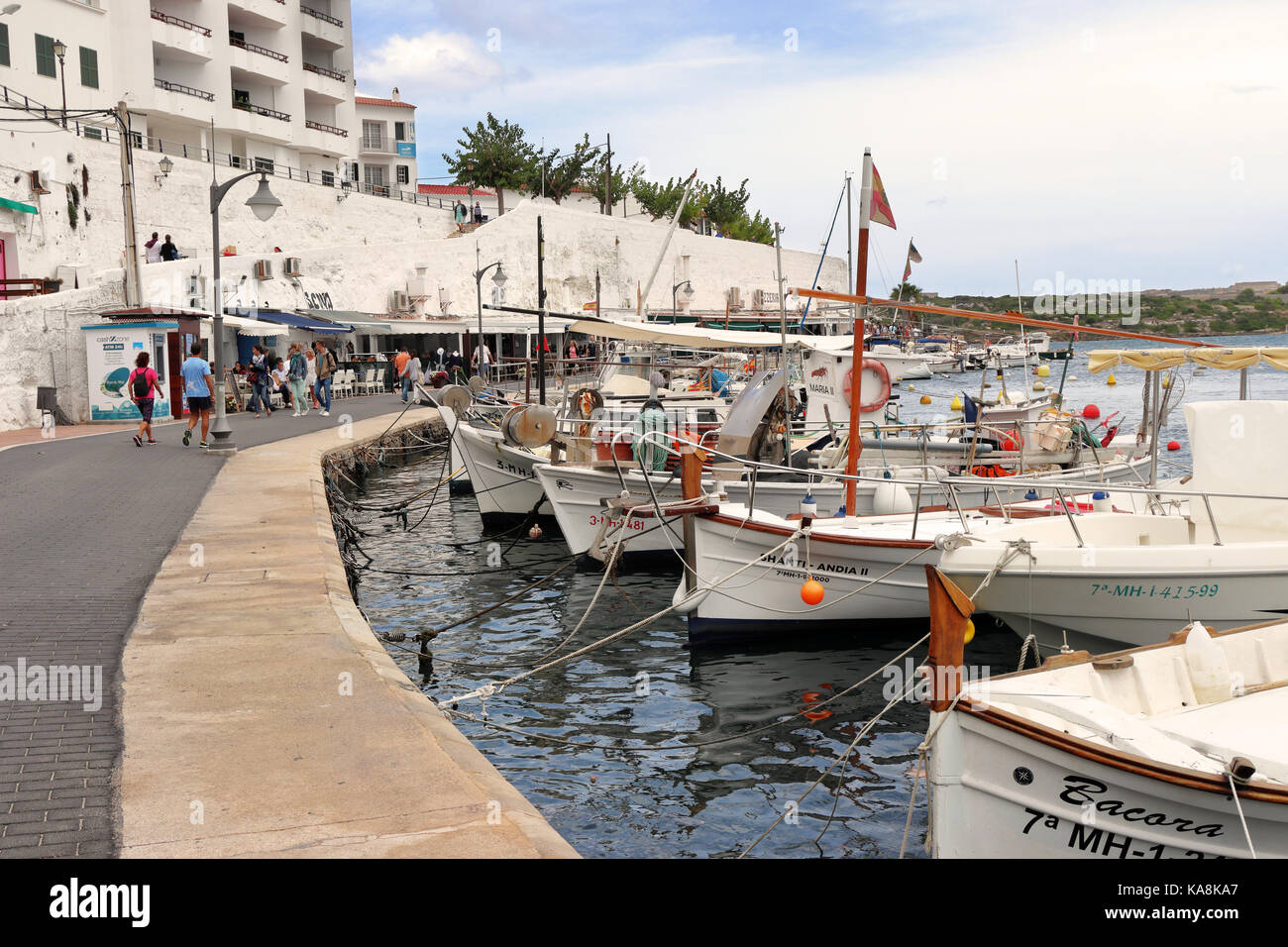 Es Castell in Minorca with fishing boats and yachts moored on the quay ...