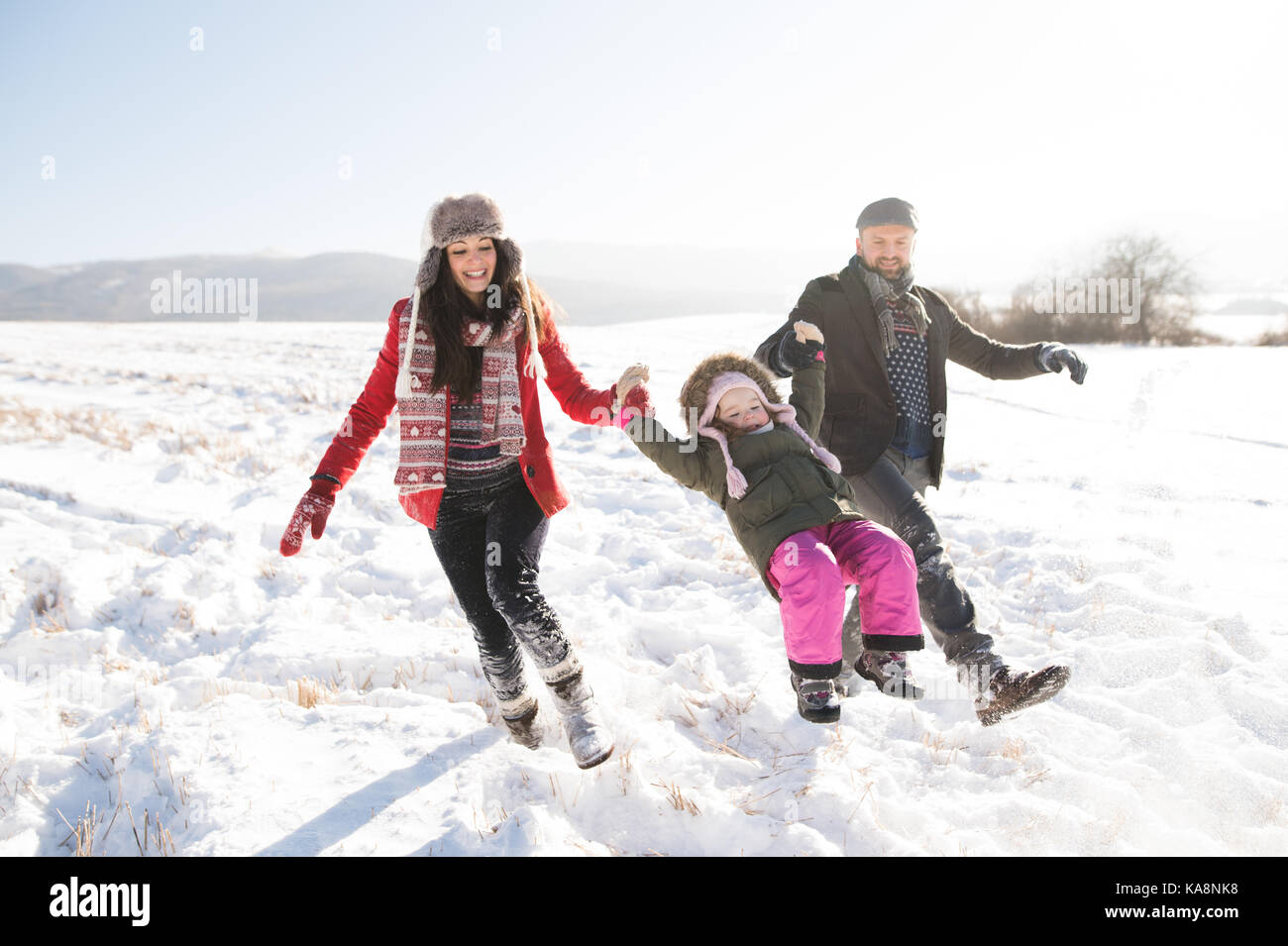 Father and mother with their daughter, playing in the snow Stock Photo ...