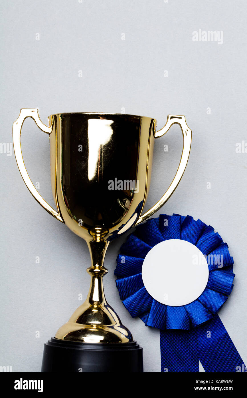 Gold trophy and winner rosette Stock Photo - Alamy