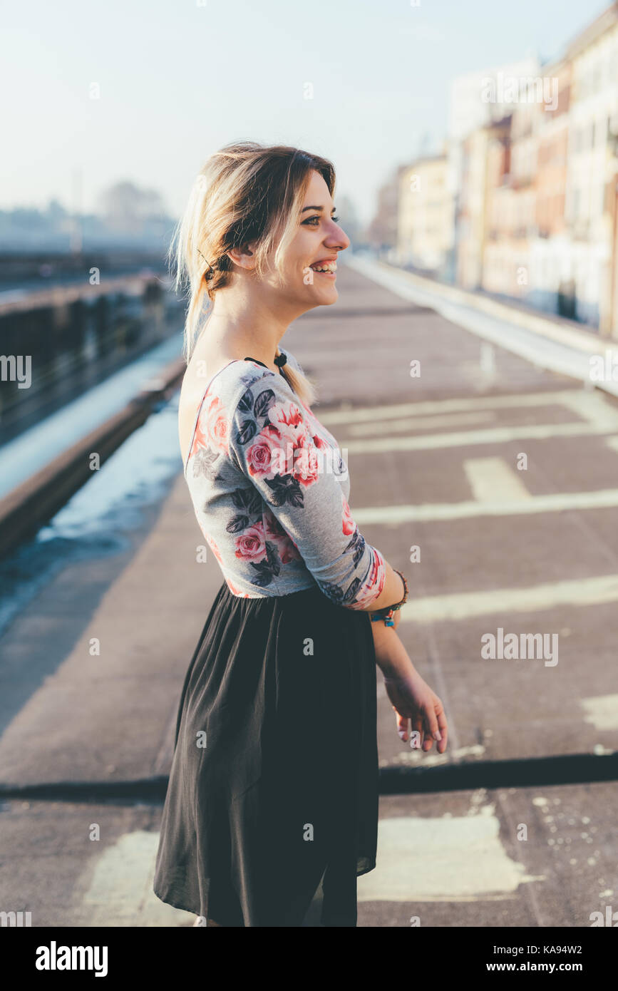 sideway view young woman outdoor back light having fun looking camera ...