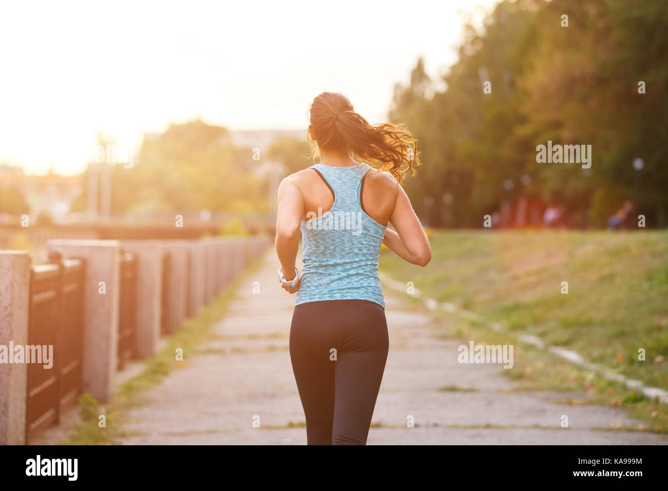 Young smiling sporty woman running in park in the morning. Fitness girl ...