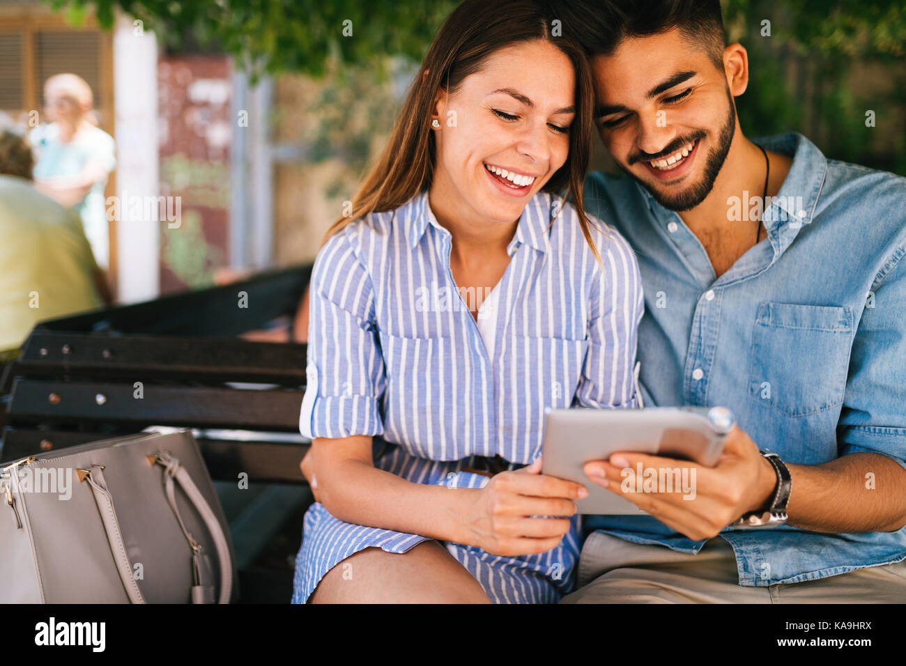 Young attractive couple on date sitting on bench Stock Photo - Alamy