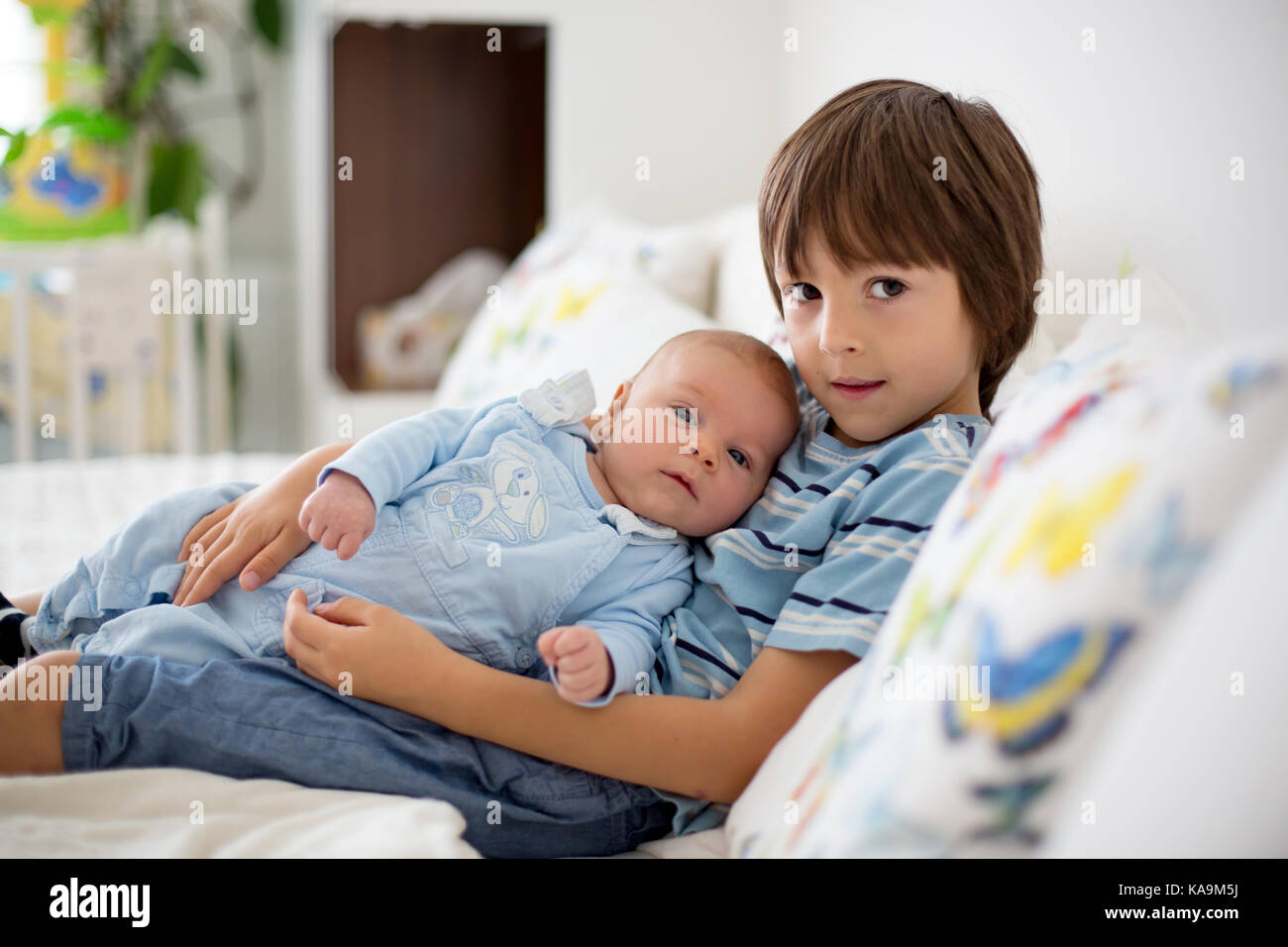 Beautiful boy, hugging with tenderness and care his newborn baby ...