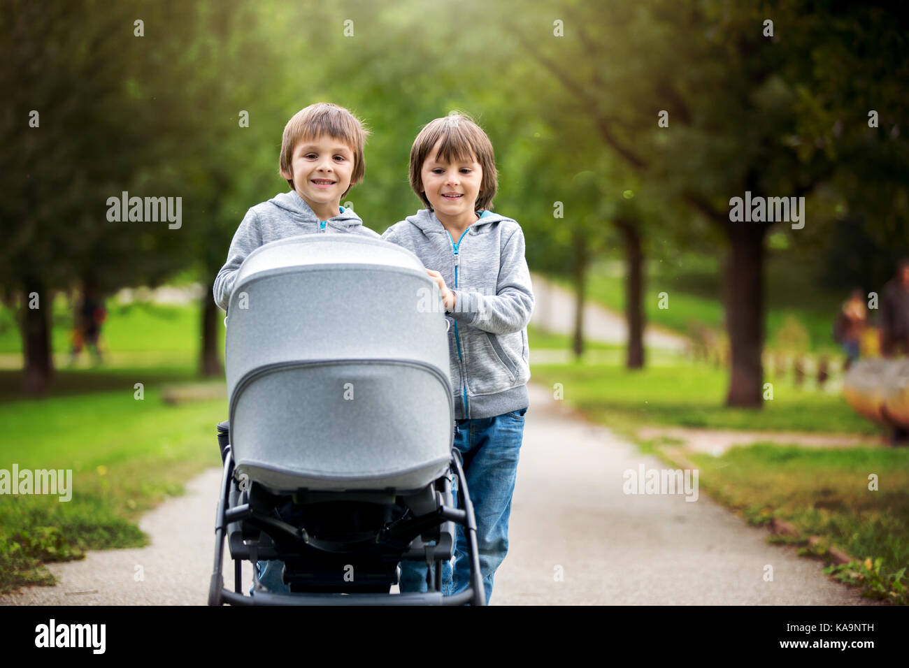 Two children, boys, pushing stroller with little baby in the park Stock ...