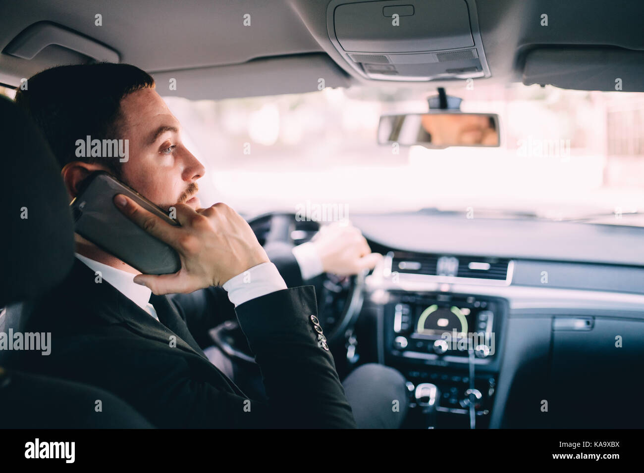Man looking at mobile phone while driving a car Stock Photo - Alamy