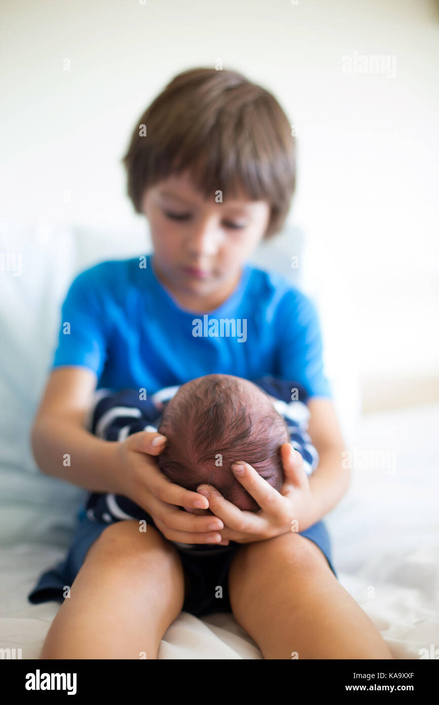 Cute boy, brother, meeting for the first time his new baby brother at ...