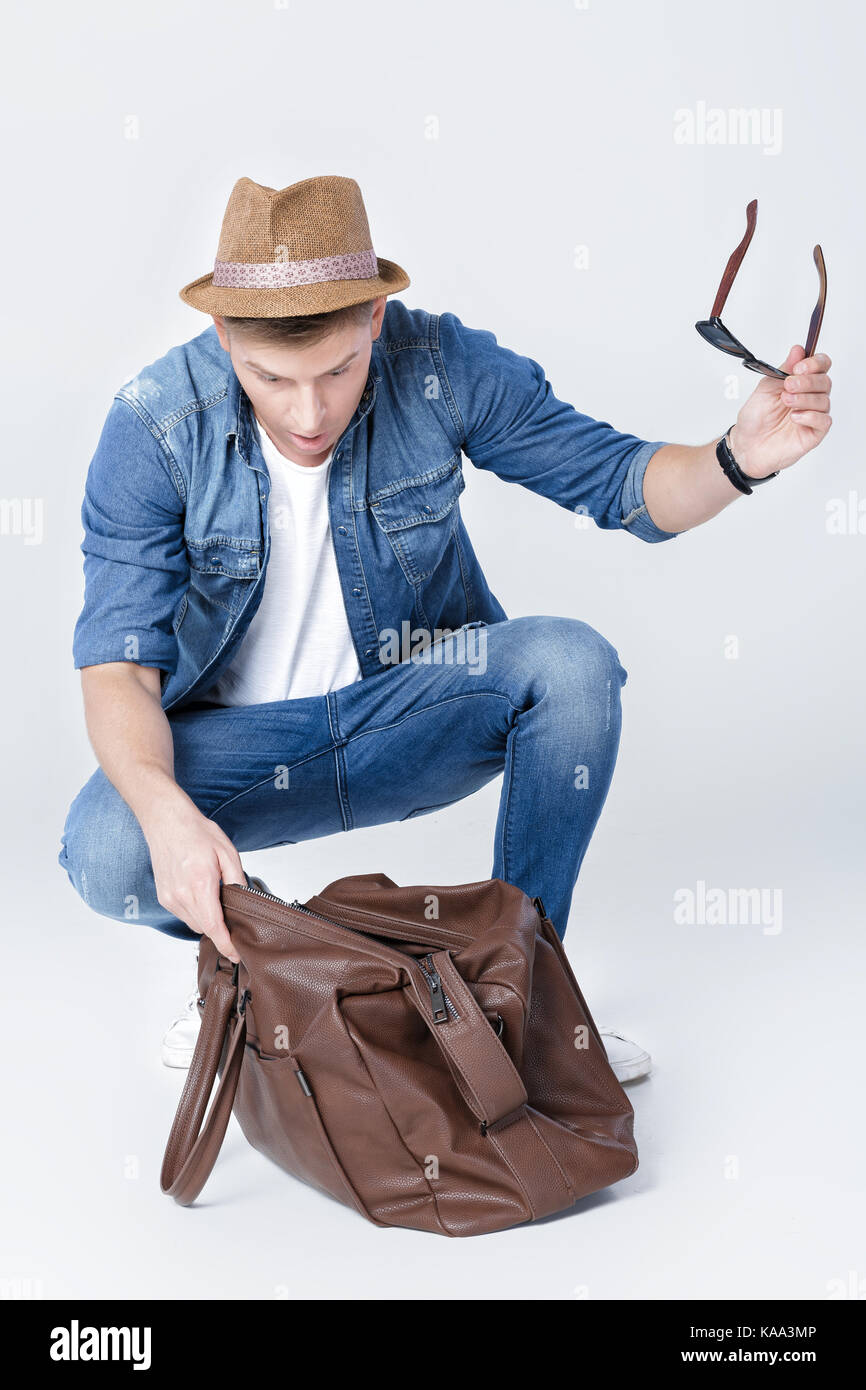 surprised man in a hat looks in an empty leather bag Stock Photo - Alamy