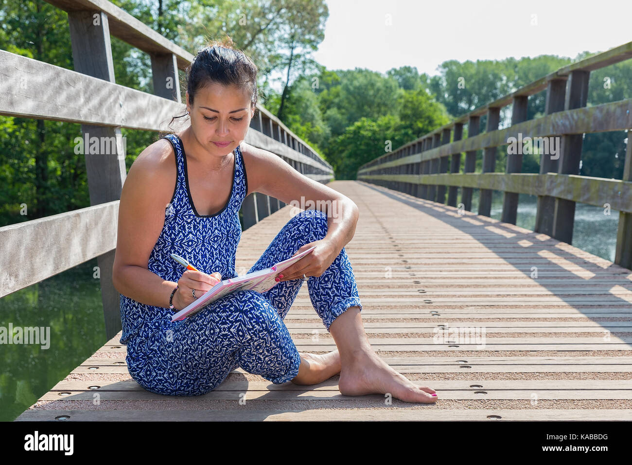 Young female writer sitting on wooden bridge in nature Stock Photo - Alamy