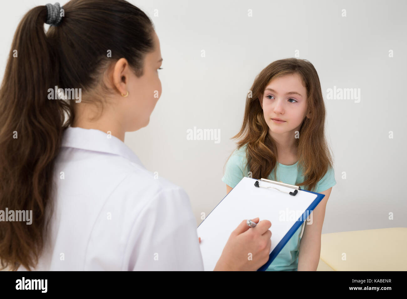 Female Doctor Writing Prescription On Clipboard In Front Of Patient ...