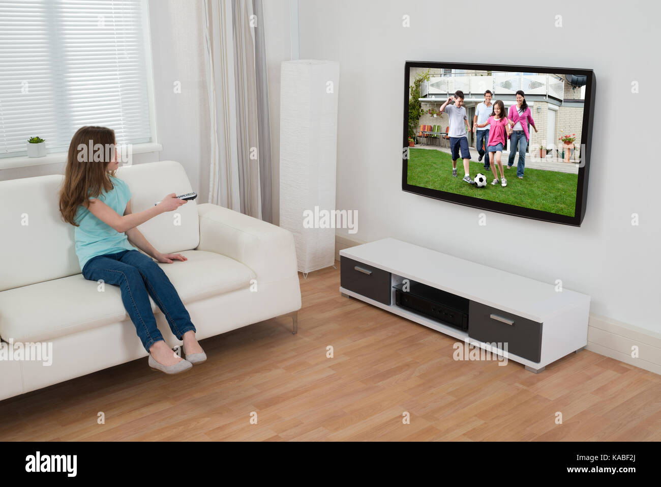 Girl Sitting On Sofa Watching Television In House Stock Photo - Alamy