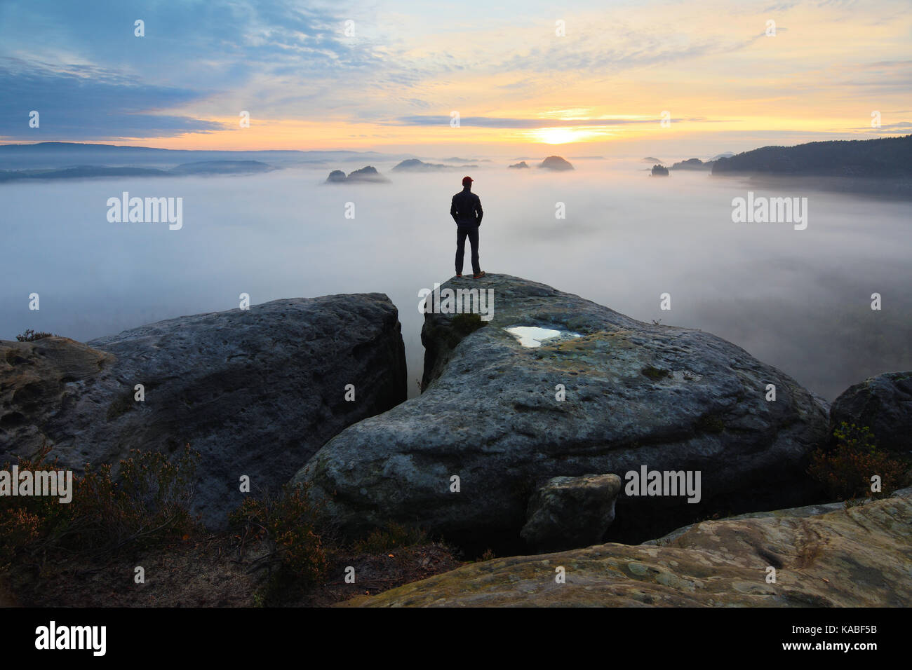 Hiker on rock end above valley. Man watch over misty and autumnal ...