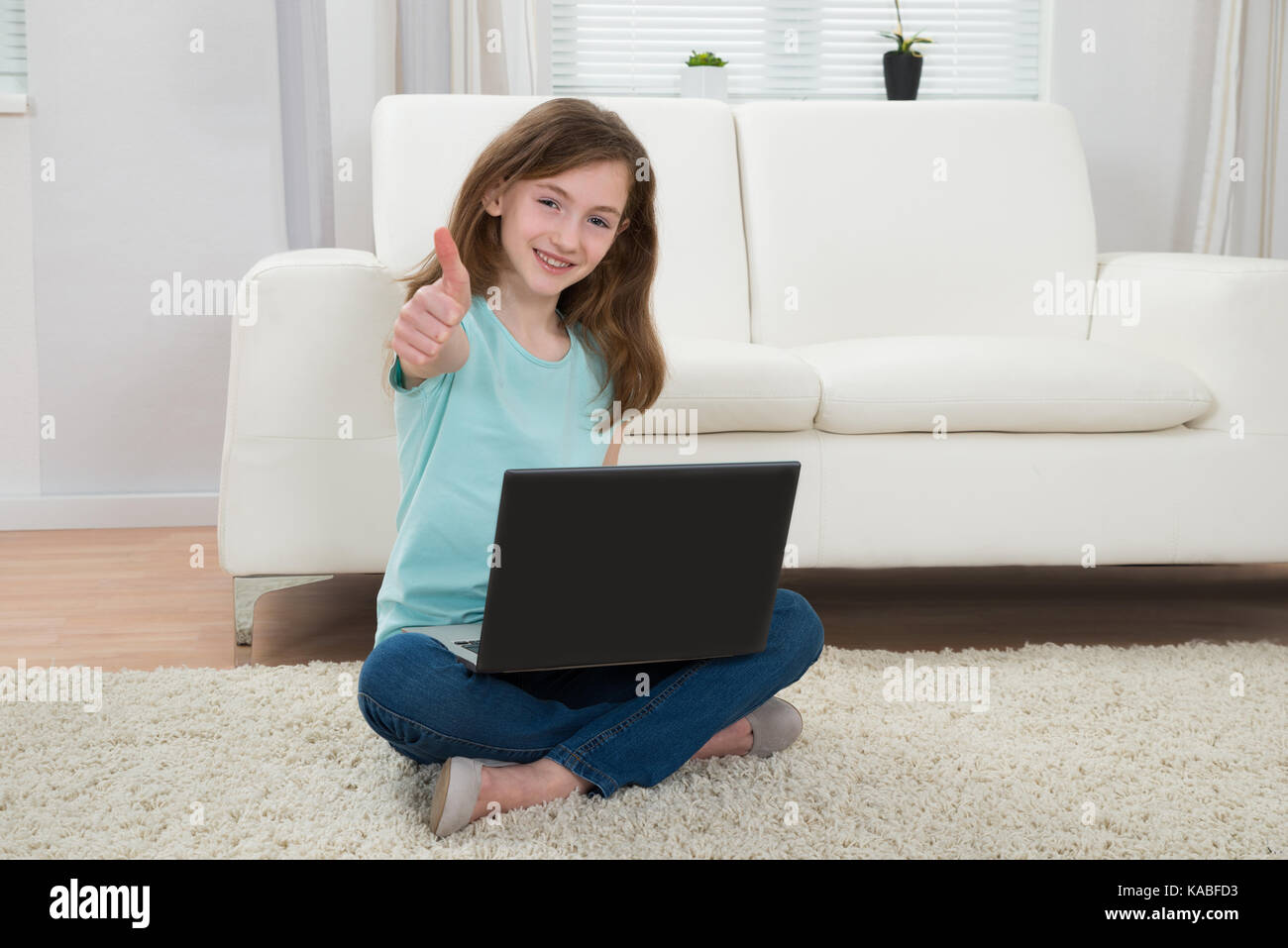 Girl Sitting In Front Of Sofa Using Laptop In Living Room Stock Photo ...