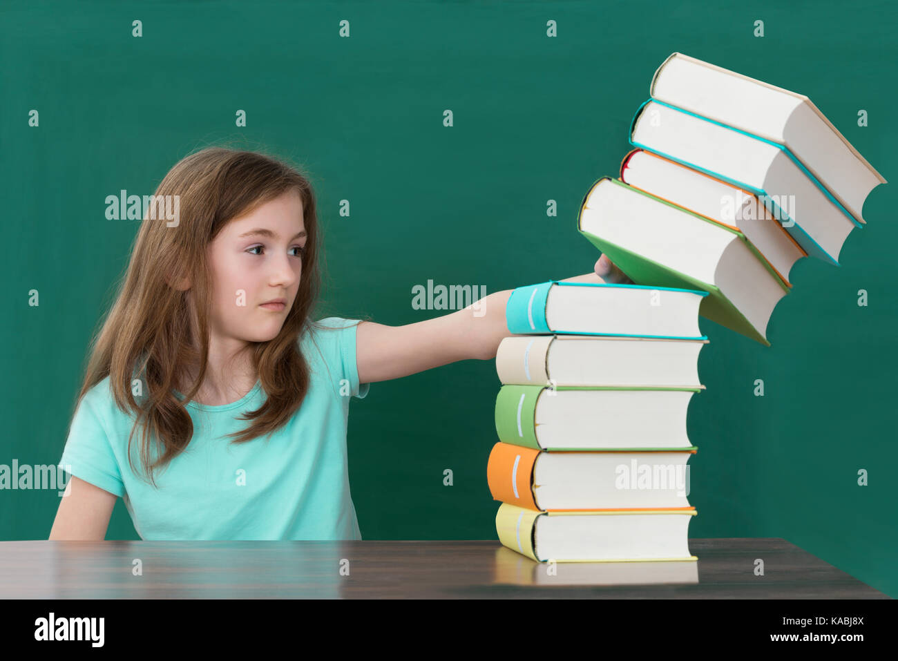 Student At Desk Pushing Stack Of Colorful Books In Classroom Stock ...