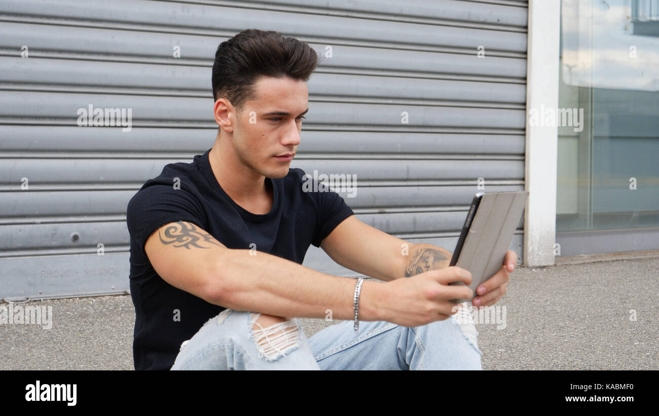 Young man using tablet PC outdoor in city Stock Photo - Alamy