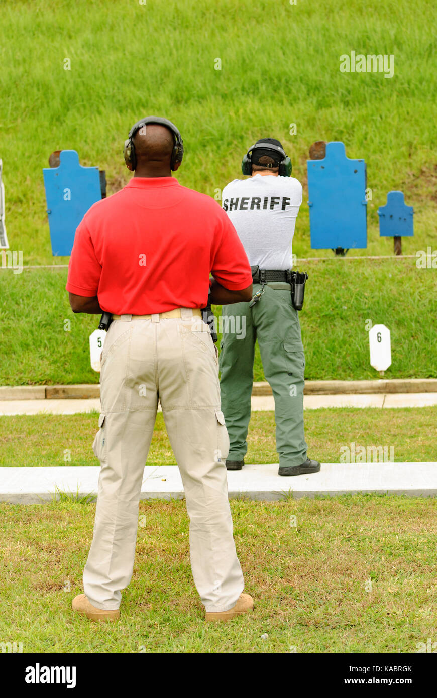 Firearms instructor oversees a law enforcement officer on the shooting ...