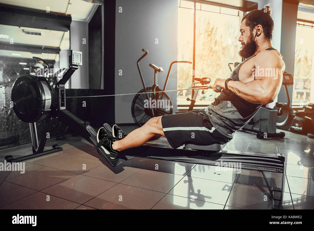 Muscular fit man using rowing machine at gym Stock Photo - Alamy