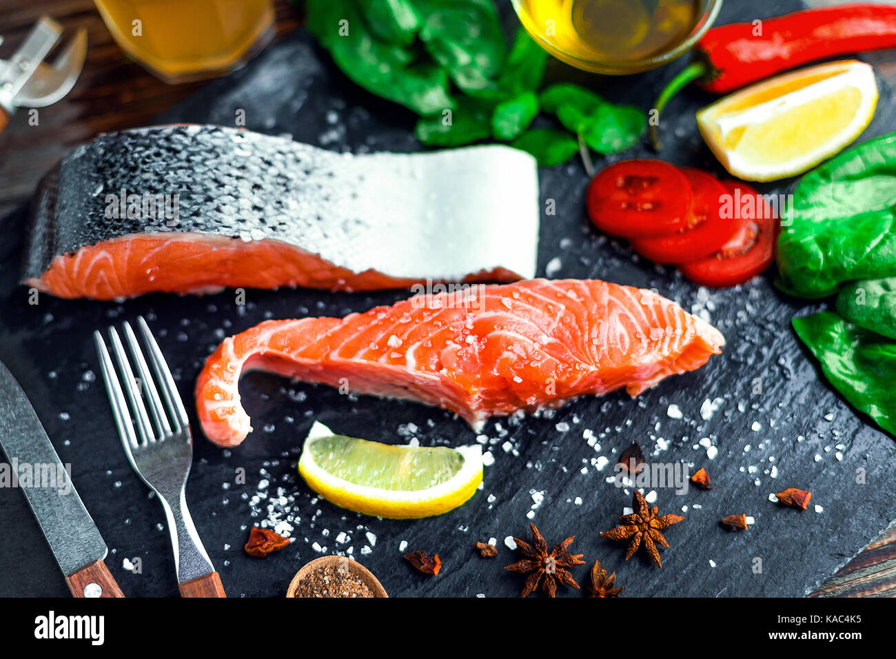 Raw salmon fillet and ingredients for cooking on a dark background in a ...
