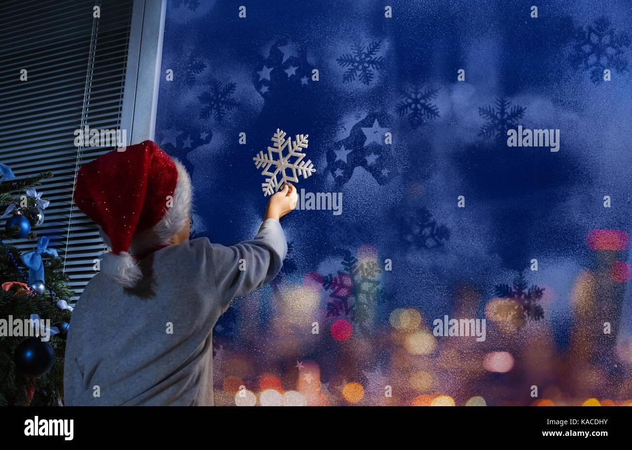Little boy putting snowflake on the window Stock Photo - Alamy