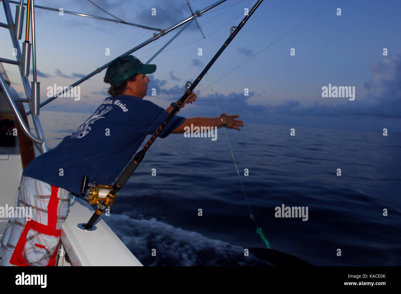 An offshore fisherman watches and adjusts his trolling rods while deep ...