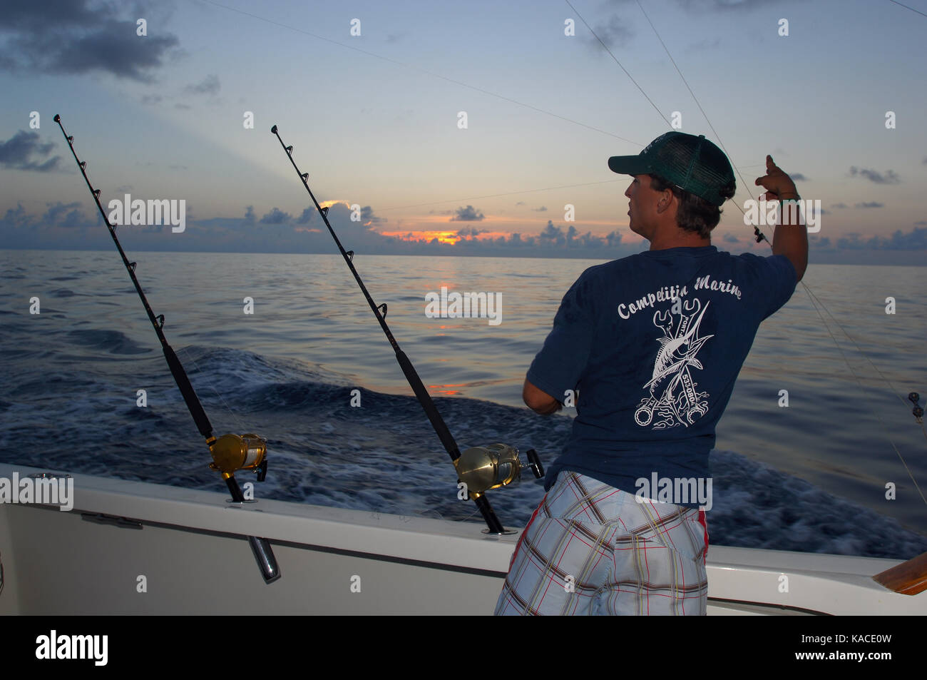 An offshore fisherman watches and adjusts his trolling rods while deep ...