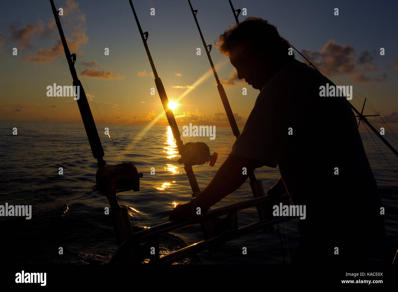 An offshore fisherman watches and adjusts his trolling rods while deep ...
