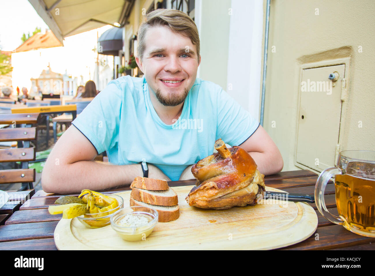 man eating knuckle of pork and drinks beer Stock Photo - Alamy
