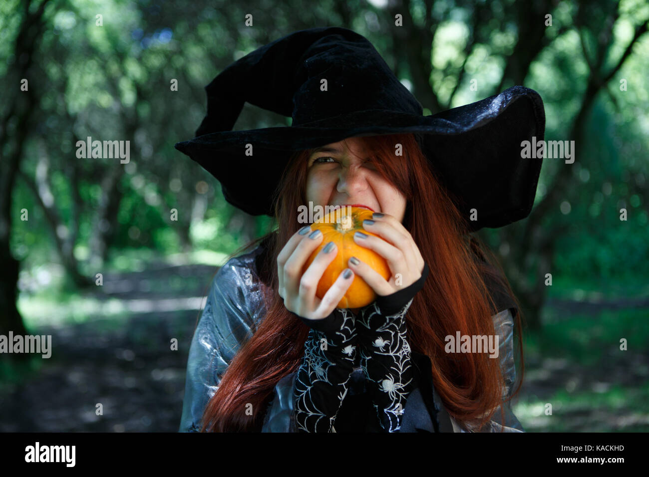 Image of witch biting pumpkin in dark forest Stock Photo - Alamy