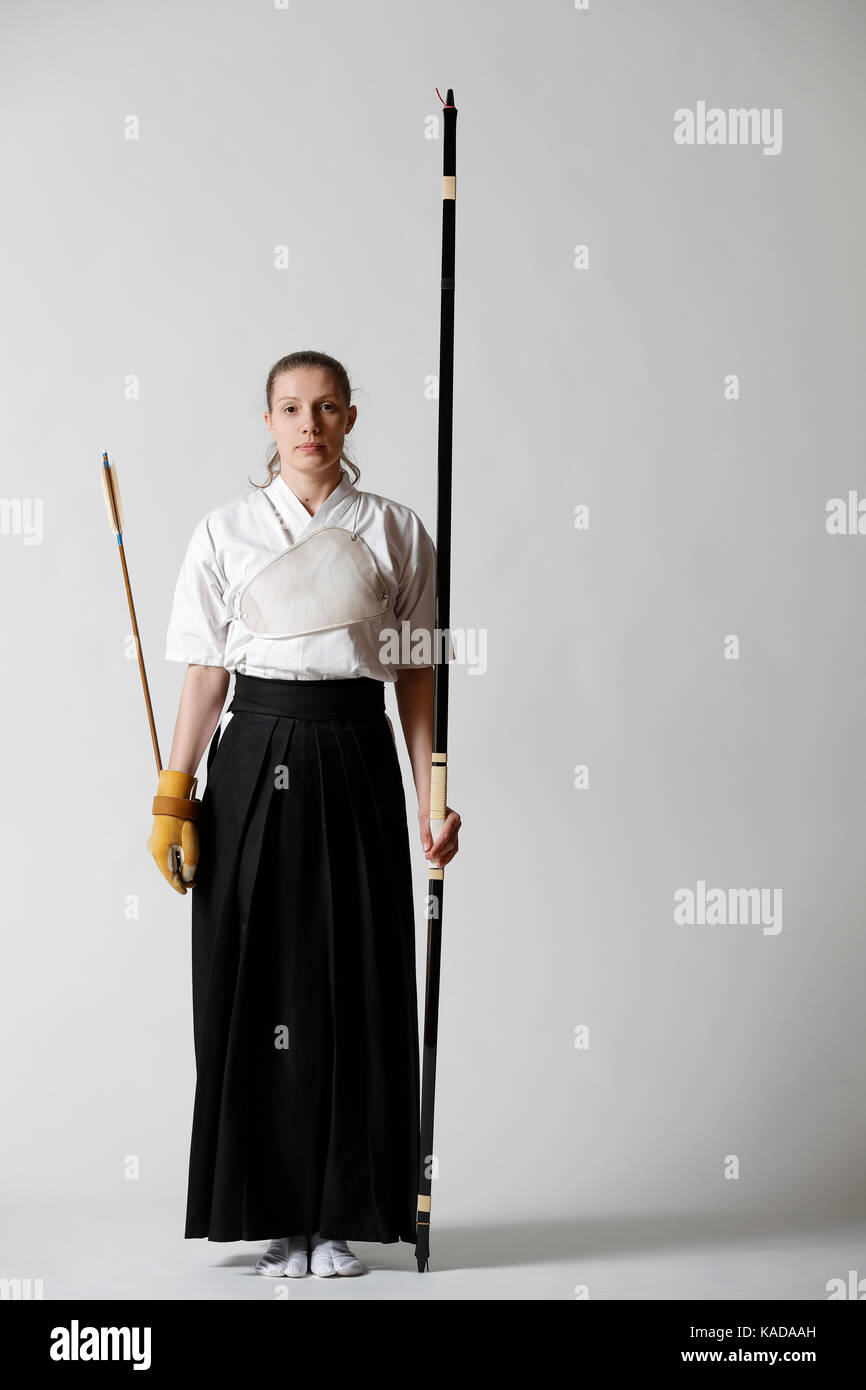 Caucasian woman practicing traditional Kyudo Japanese archery on white ...