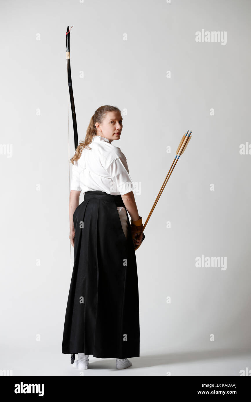 Caucasian woman practicing traditional Kyudo Japanese archery on white ...