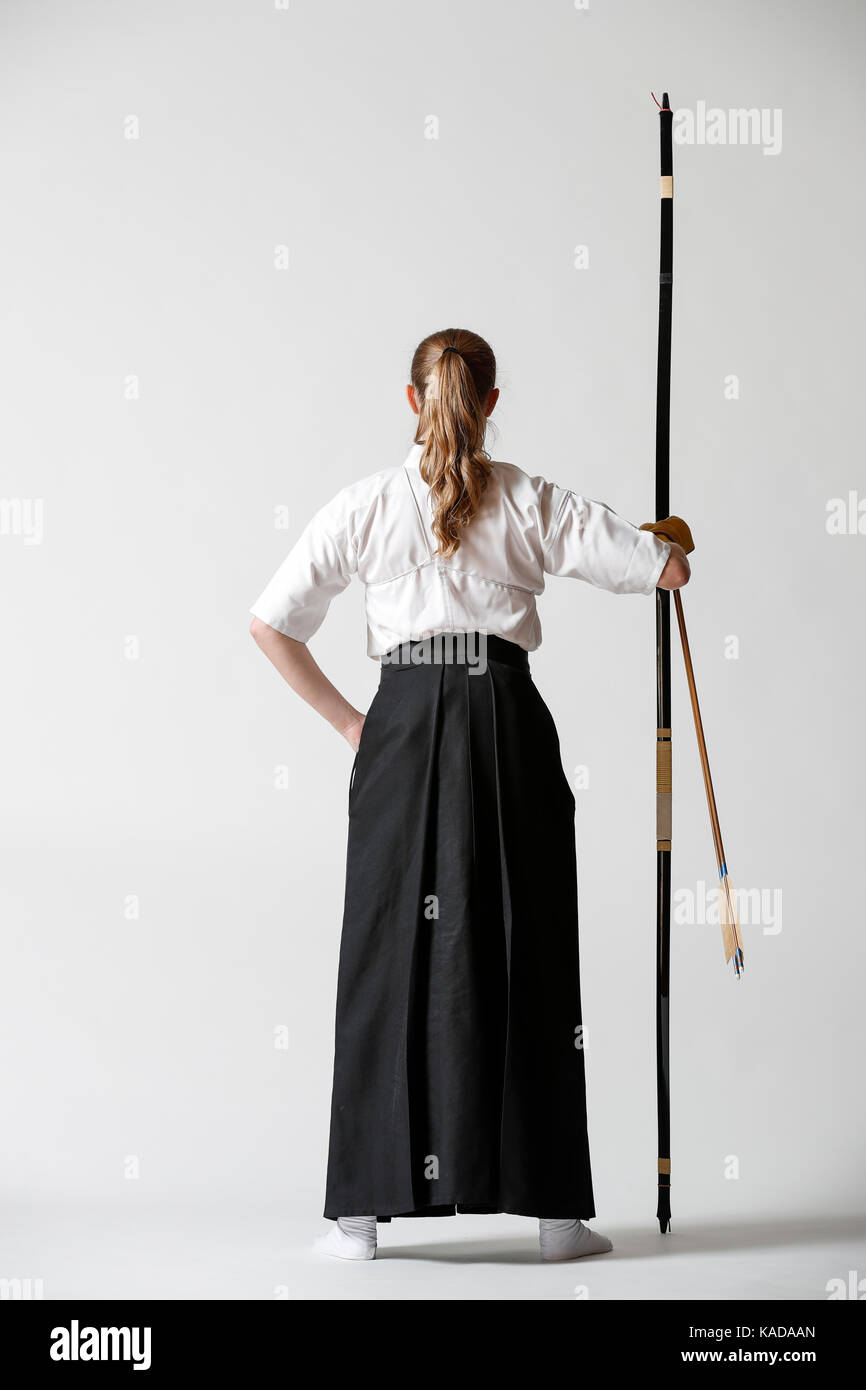 Caucasian woman practicing traditional Kyudo Japanese archery on white ...