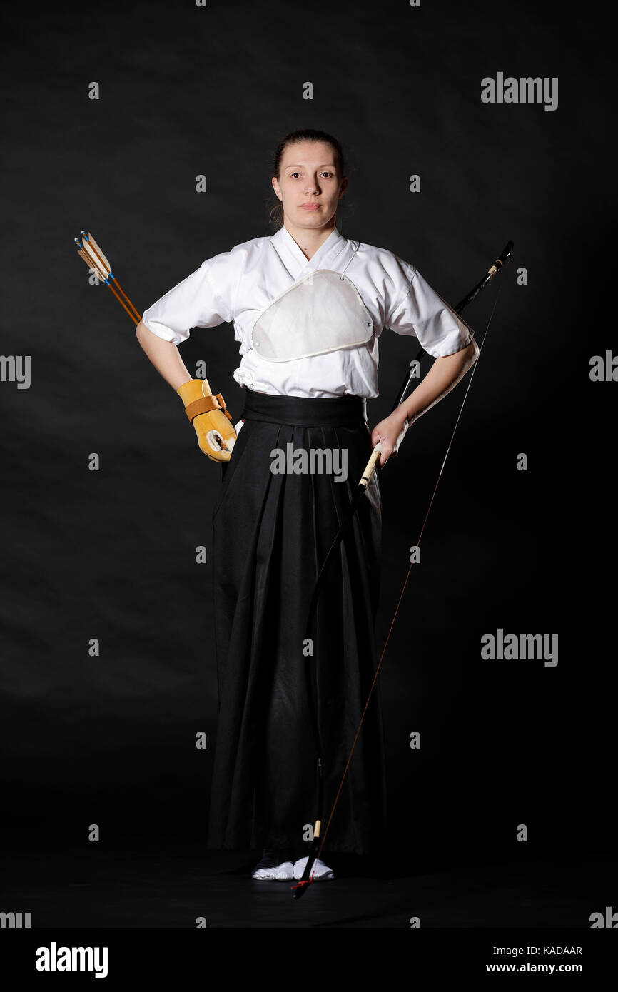 Caucasian woman practicing traditional Kyudo Japanese archery on black ...