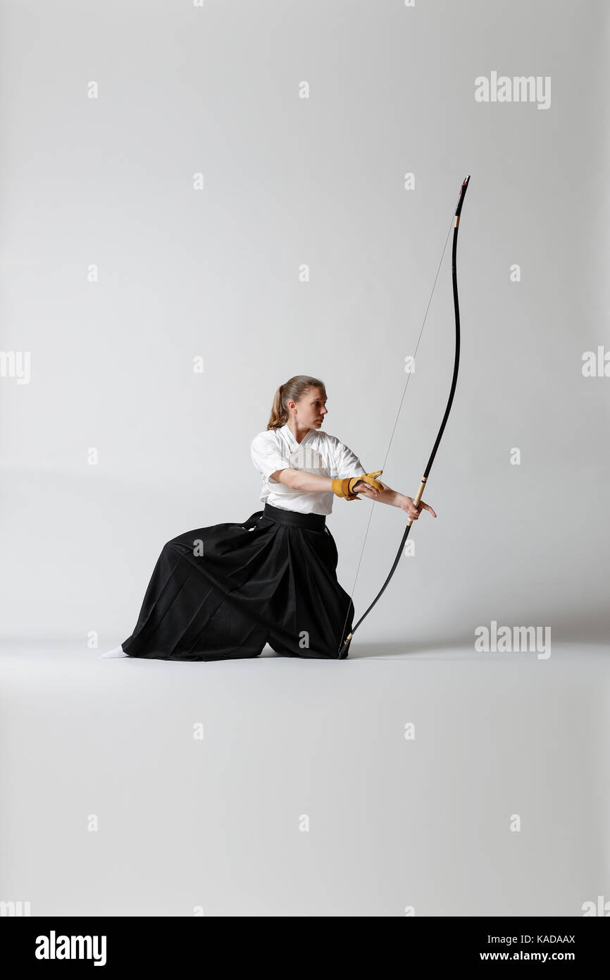 Caucasian woman practicing traditional Kyudo Japanese archery on white ...