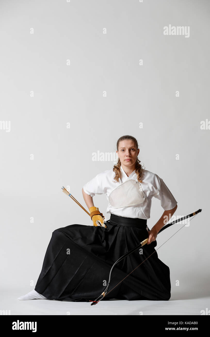 Caucasian woman practicing traditional Kyudo Japanese archery on white ...