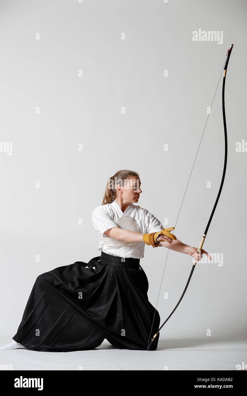 Caucasian woman practicing traditional Kyudo Japanese archery on white ...