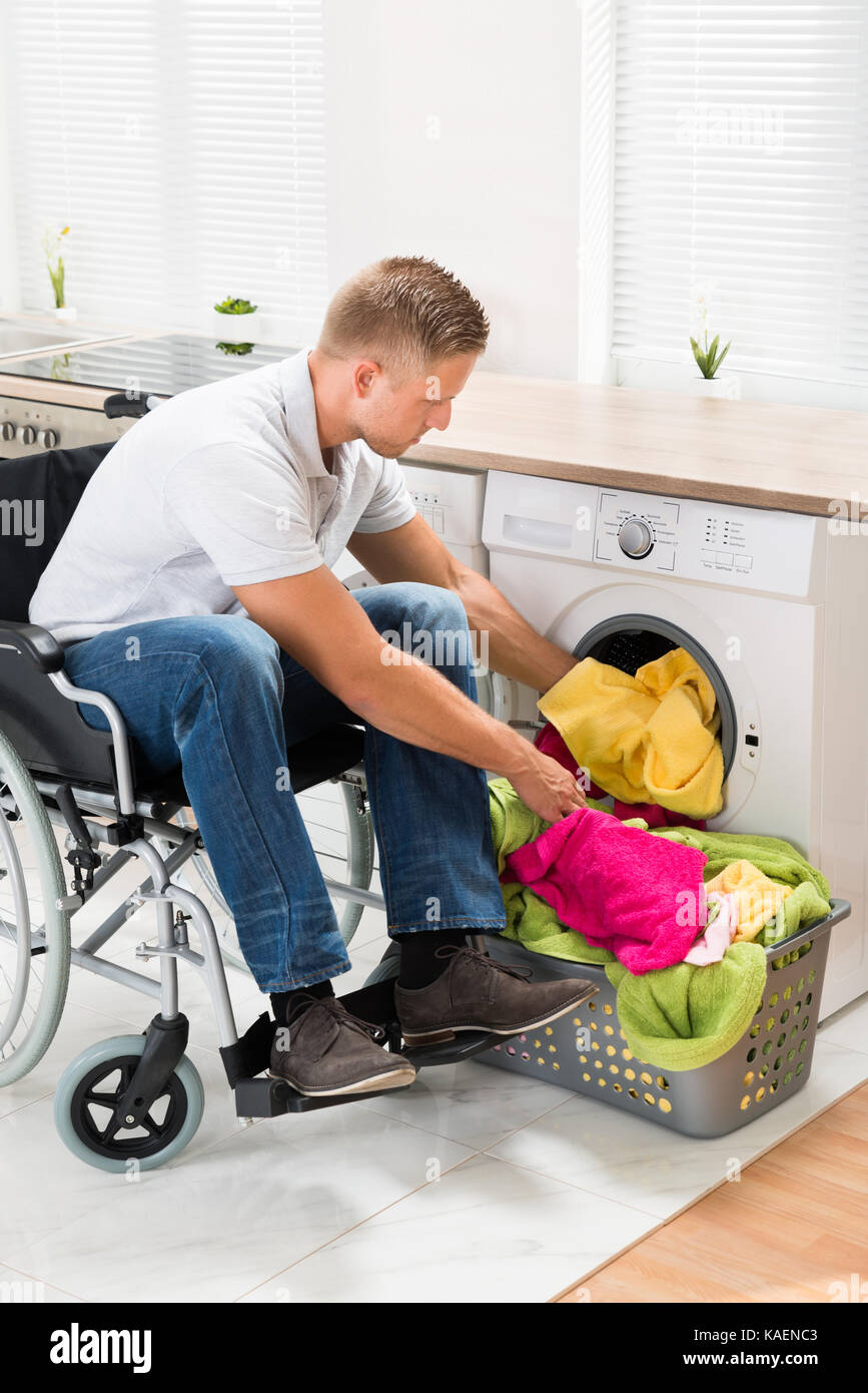 Young Disabled Man On Wheelchair Putting Towels Into The Washing ...