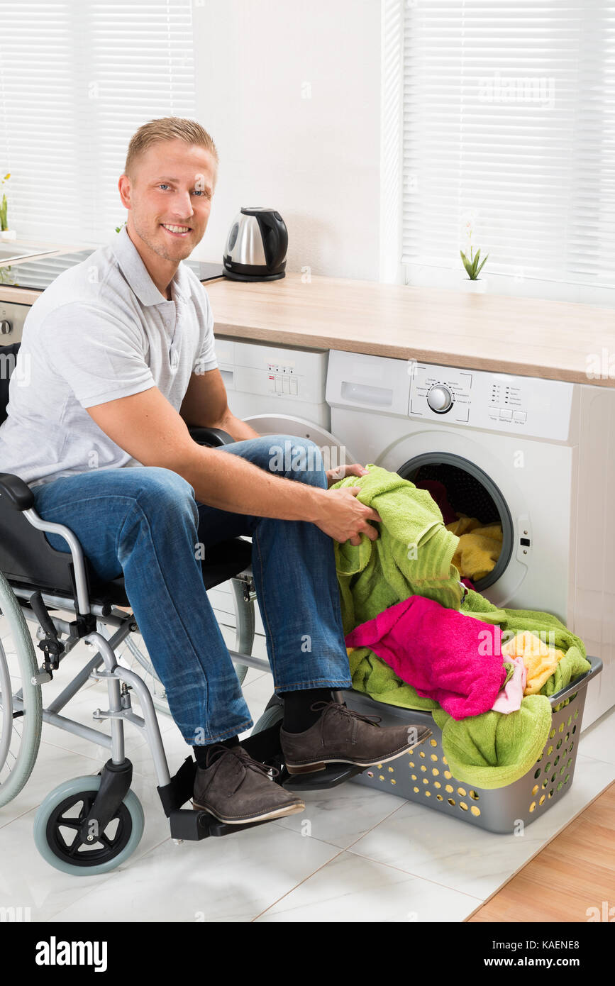Young Happy Man On Wheelchair Putting Clothes Into The Washing Machine ...