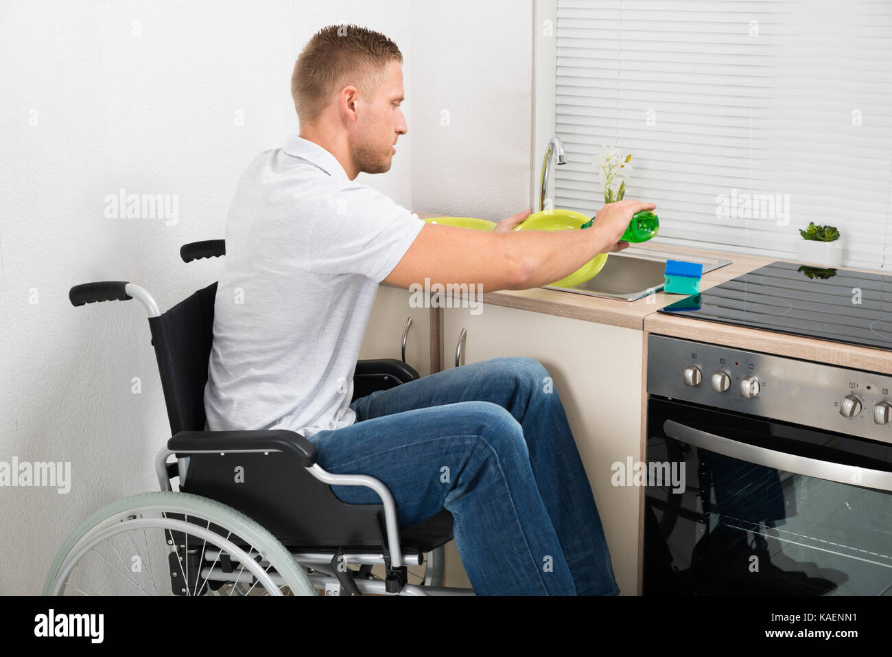 Young Disabled Man On Wheelchair Washing Dishes In The Kitchen Stock ...