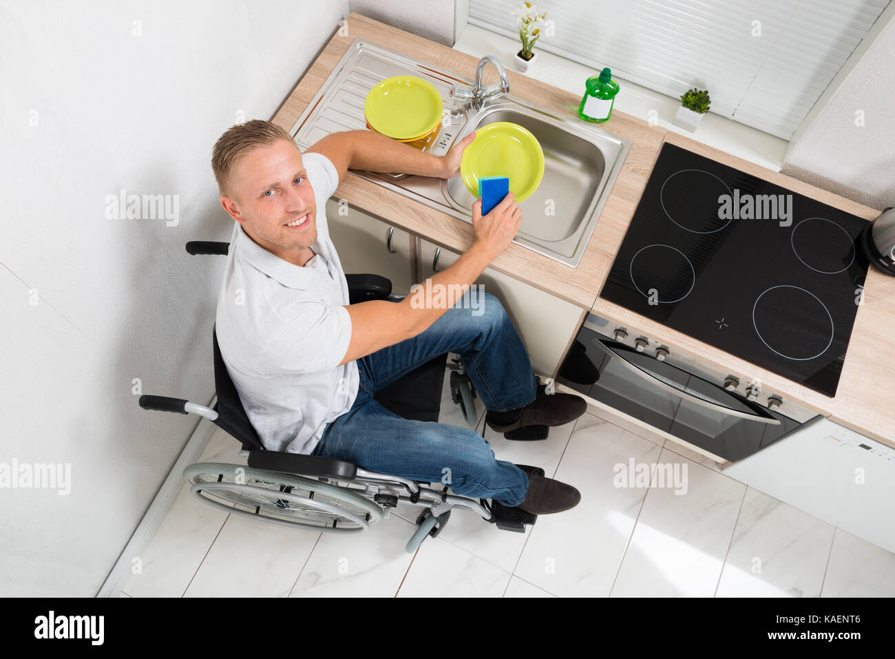 High Angle View Of Happy Man On Wheelchair With Sponge Washing Dishes ...
