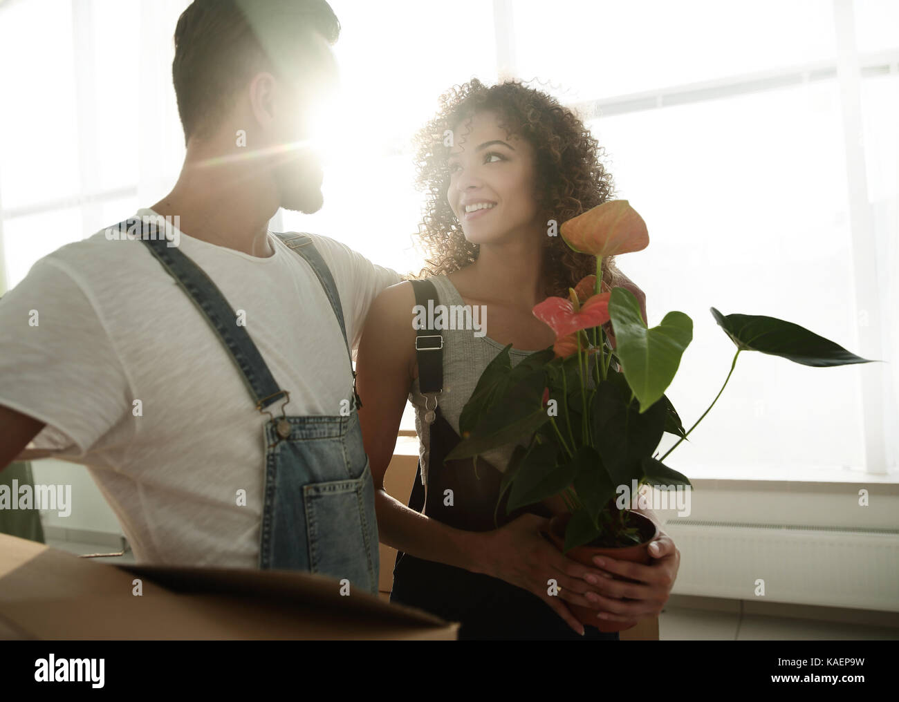 Close-up of a beautiful young couple is carrying things into a new home ...