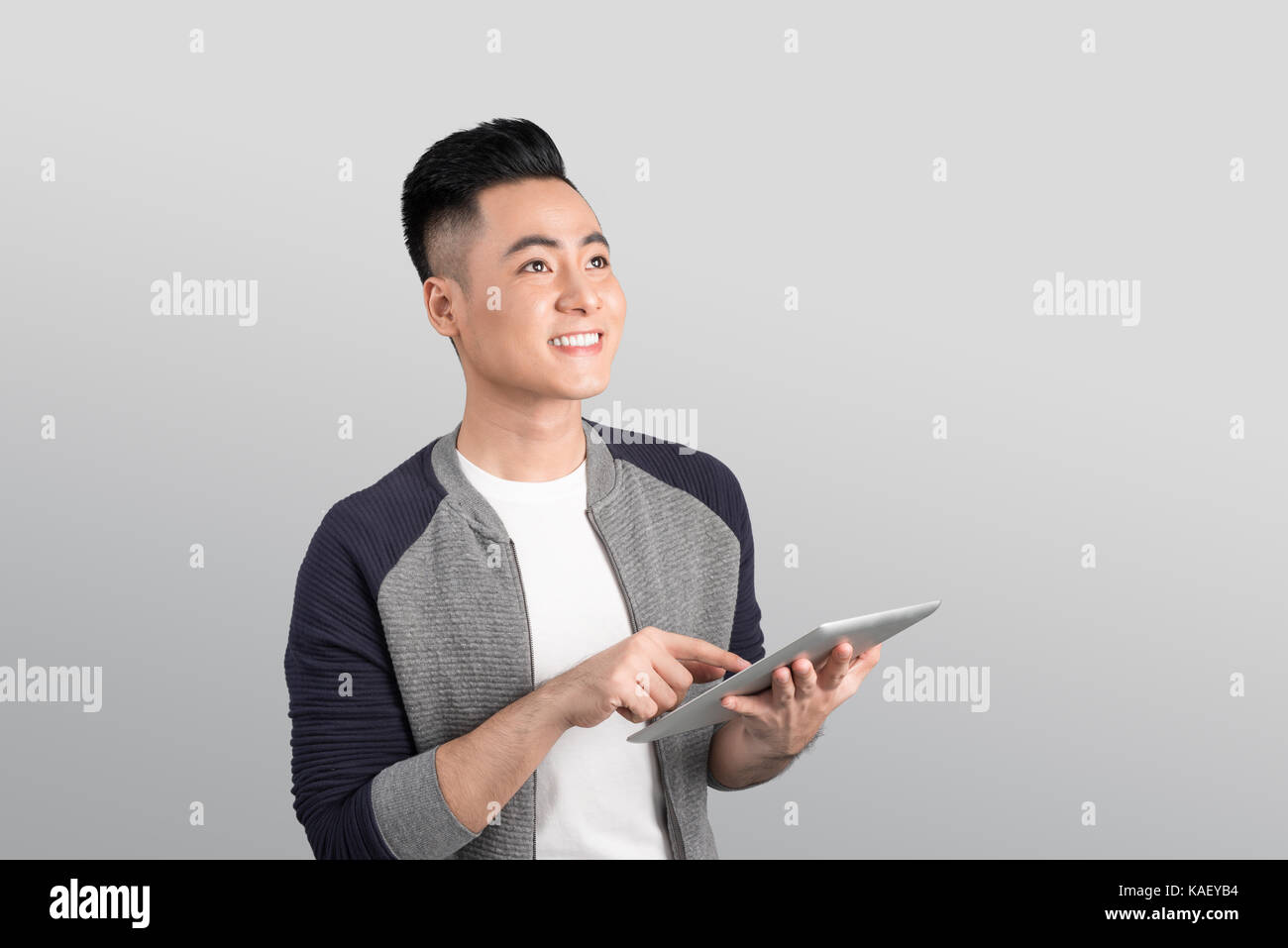 Confident young asian businessman holding digital tablet looking up ...