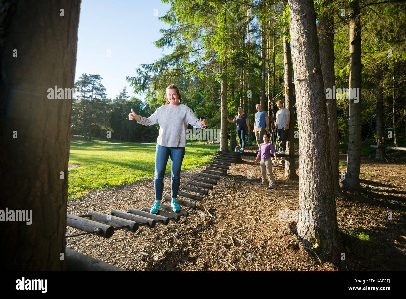 Happy Young Woman Crossing Log Bridge In Forest Stock Photo - Alamy
