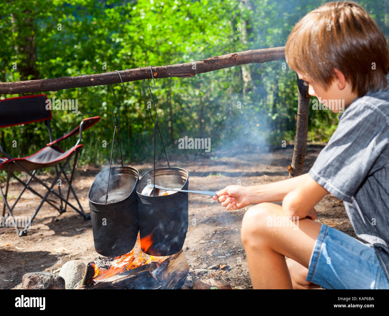 Young boy cooking camp food in cauldron on open fire Stock Photo - Alamy