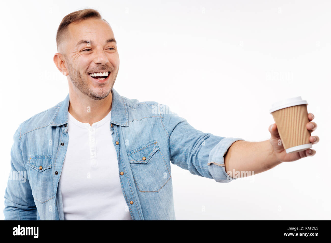 Joyful young man offering a paper cup of coffee Stock Photo - Alamy