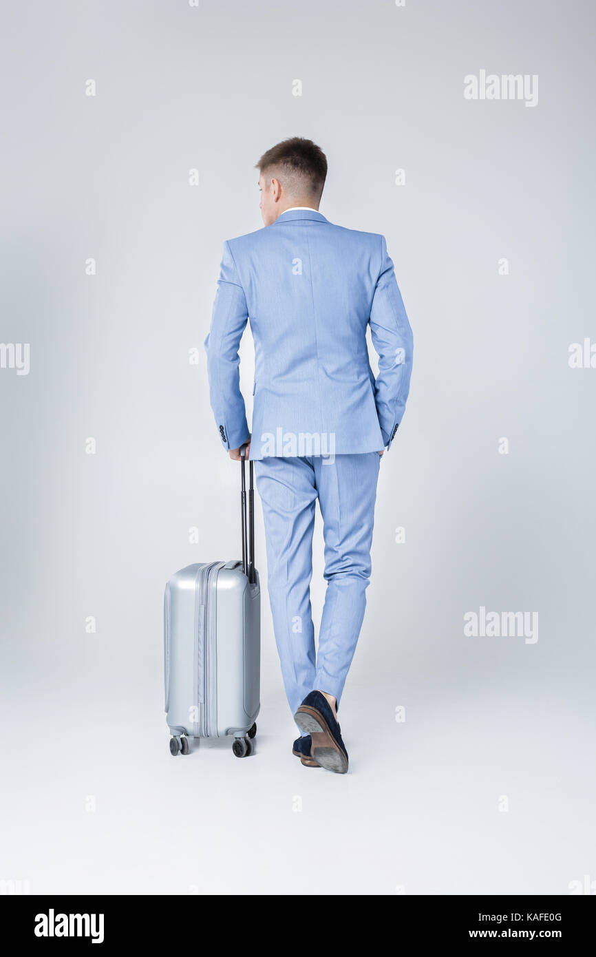 young man in blue suit with suitcase Stock Photo - Alamy